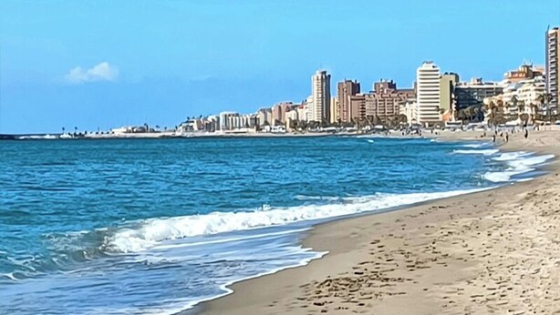 Uma praia com um horizonte urbano ao fundo.