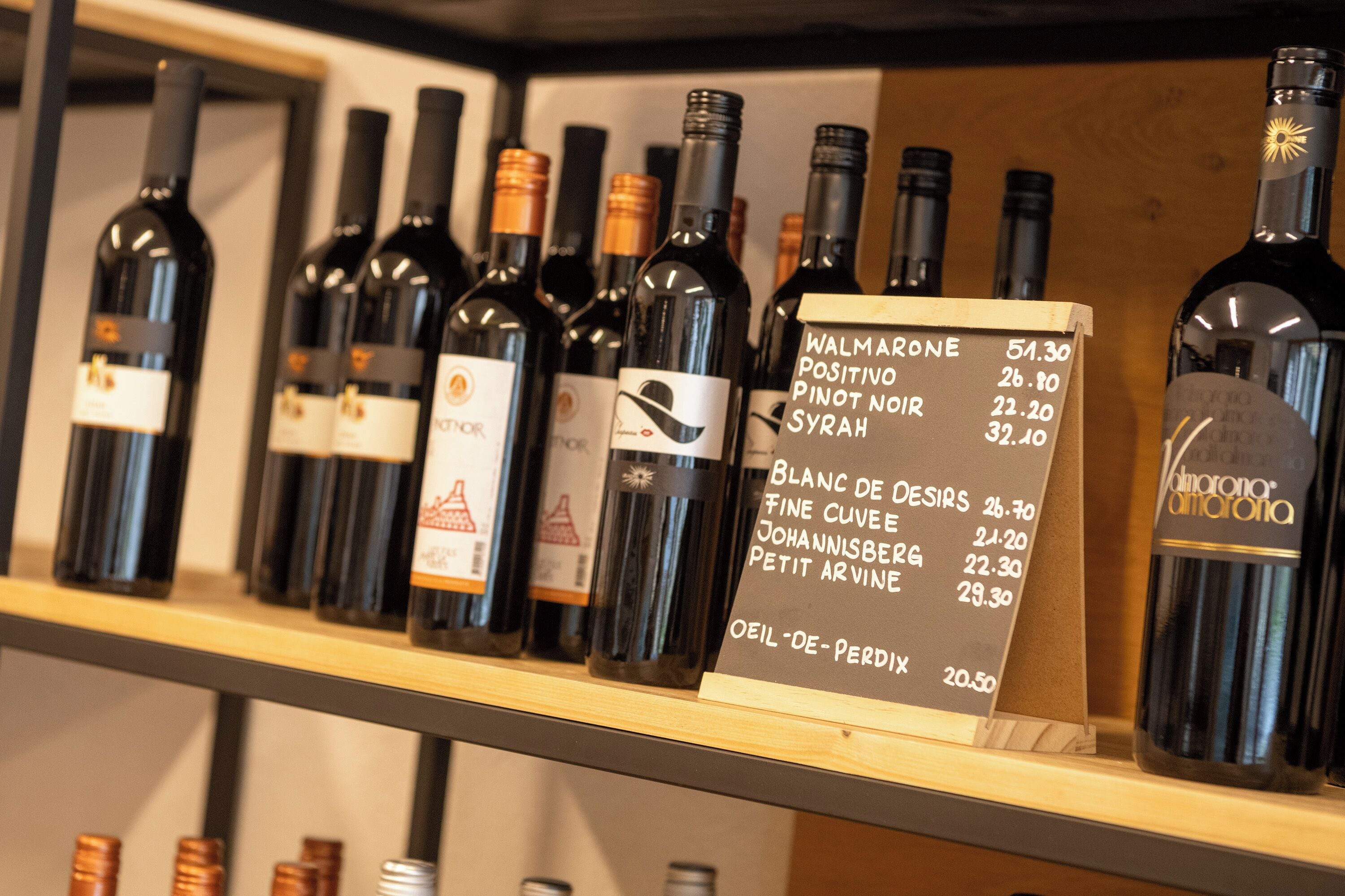 Uma estante de vinhos com várias garrafas e uma lista de preços.
