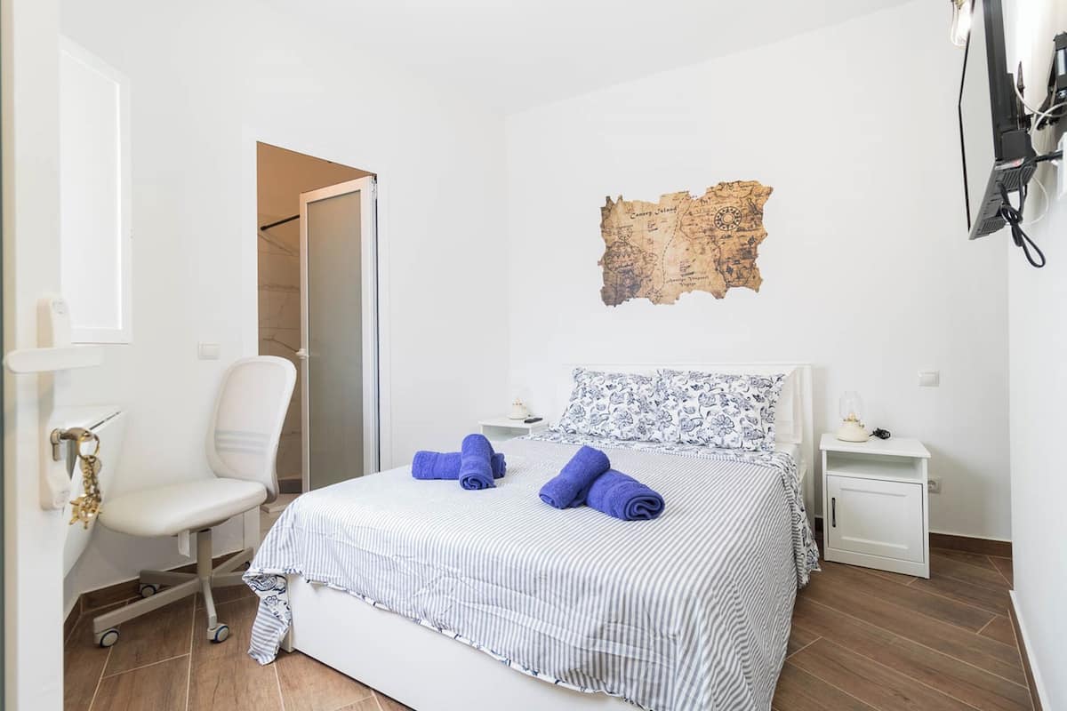 Quarto com cama, cadeira, mesa de cabeceira e mapa na parede.