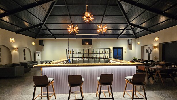 Uma área de bar com teto alto, banquetas e balcão.
