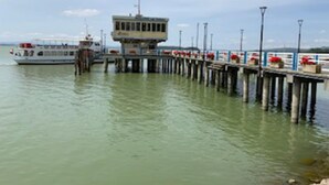 Um cais com uma torre de controle e um barco atracado no final.