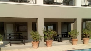 Uma área à beira da piscina com plantas em vasos e mobiliário de exterior.