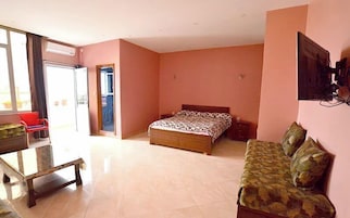 Um quarto com cama, sofá, televisão e escrivaninha.