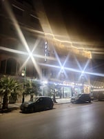 Um hotel com uma placa grande, uma rua em frente e carros estacionados.