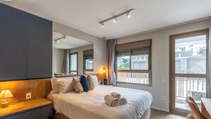 Quarto de hotel com cama, mesa de cabeceira, luminária e vista para a varanda.