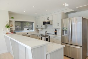 Uma cozinha moderna com armários brancos, eletrodomésticos de aço inoxidável e bancada de mármore.