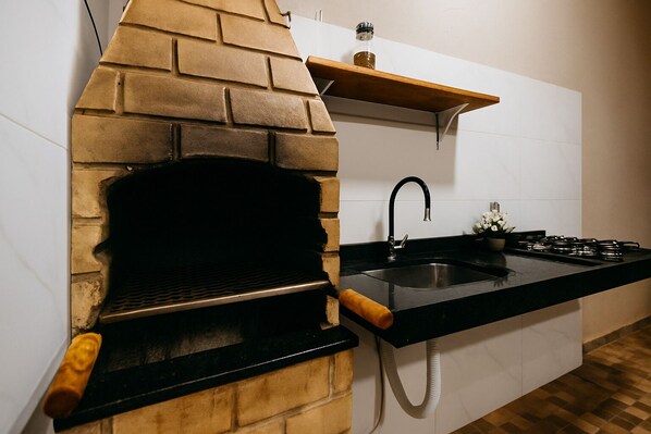 Uma cozinha com forno de tijolos, pia e fogão.