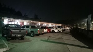 Uma fileira de caminhonetes estacionadas em frente a um edifício com letreiros iluminados.