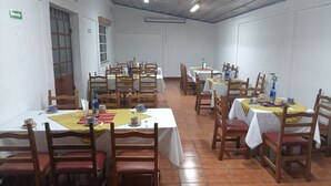 Uma área de refeições com várias mesas e cadeiras, dispostas em fileiras.