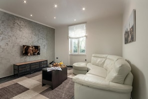 Uma sala de estar moderna com um sofá modular, uma mesa de centro, um banco e uma televisão.