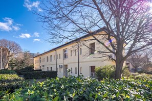 Um edifício com telhado plano, várias janelas e uma árvore em primeiro plano.