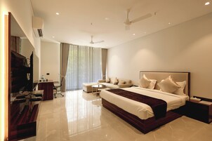 Quarto de hotel moderno com uma cama grande, uma escrivaninha, uma cadeira e uma televisão.