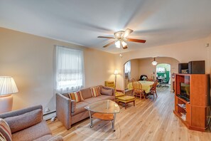 Uma sala de estar com sofá, poltrona, mesa de centro e televisão.