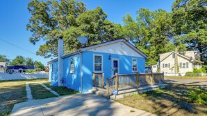 A blue house with a porch, a satellite dish, and a small front yard.