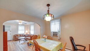 A dining area with a table set for four, surrounded by wooden chairs, a ceiling fan, and a decorative chandelier.