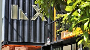 Um edifício moderno com fachada preta, janelas amplas e um letreiro visível 'LUX'.