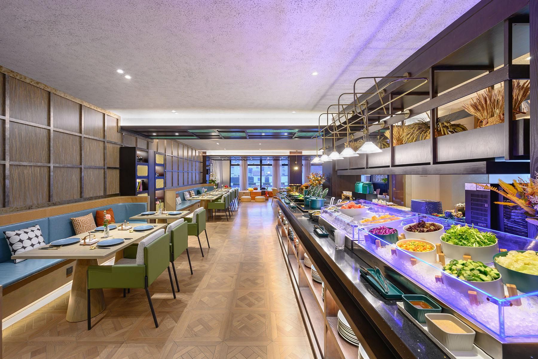 Restaurante estilo buffet com várias áreas de estar e diversas opções de comida expostas em um balcão refrigerado.