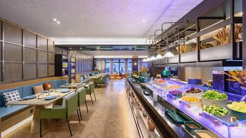 Restaurante estilo buffet com várias áreas de estar e diversas opções de comida expostas em um balcão refrigerado.