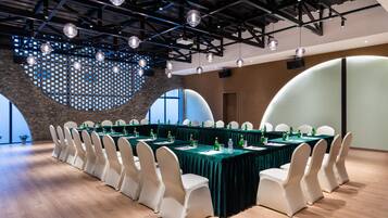 Sala de conferência com várias mesas, cadeiras brancas e design moderno no teto.