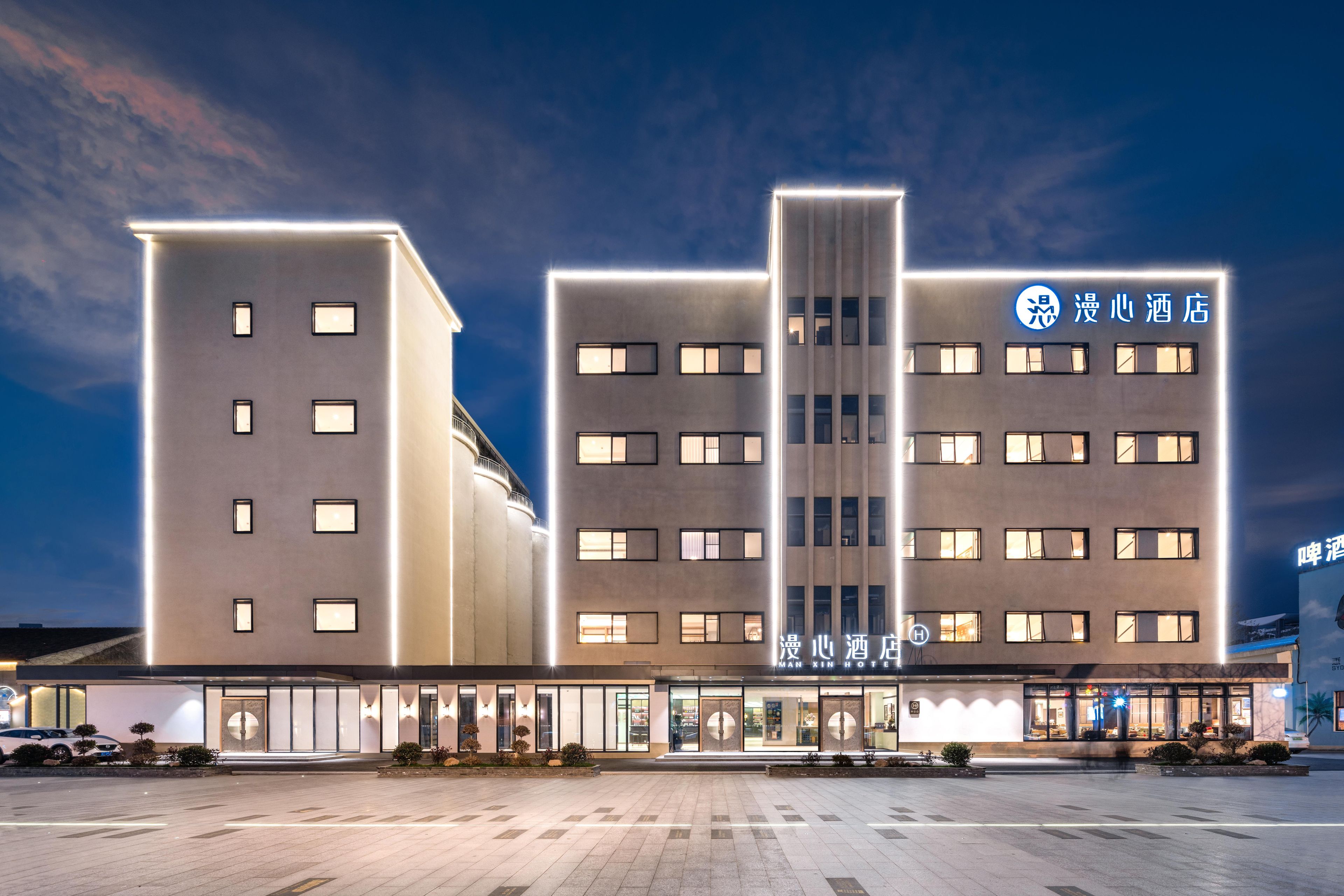 Um hotel moderno com uma torre central, vários andares e fachada bem iluminada.