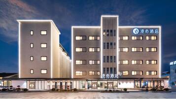 Um hotel moderno com uma torre central, vários andares e fachada bem iluminada.