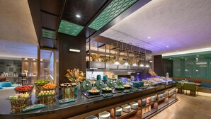 Uma área de buffet com diversos alimentos e um espaço de refeições com mesas e cadeiras.