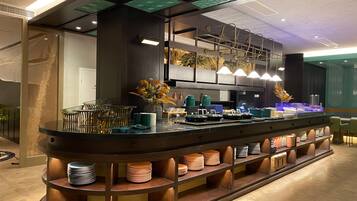 Uma área de bar moderna com ilha central, prateleiras com pratos empilhados e luminárias pendentes.