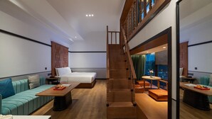 Quarto de hotel moderno com cama, sofá, escada de madeira e vista para a cidade.
