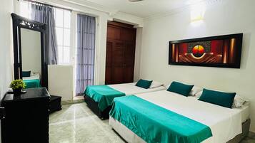 Quarto de hotel com duas camas, um espelho grande, um ventilador de teto e um quadro na parede.