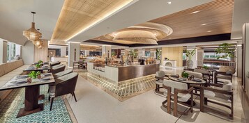 Um hall de hotel moderno com área de bar central, espaços para sentar e piso estampado.