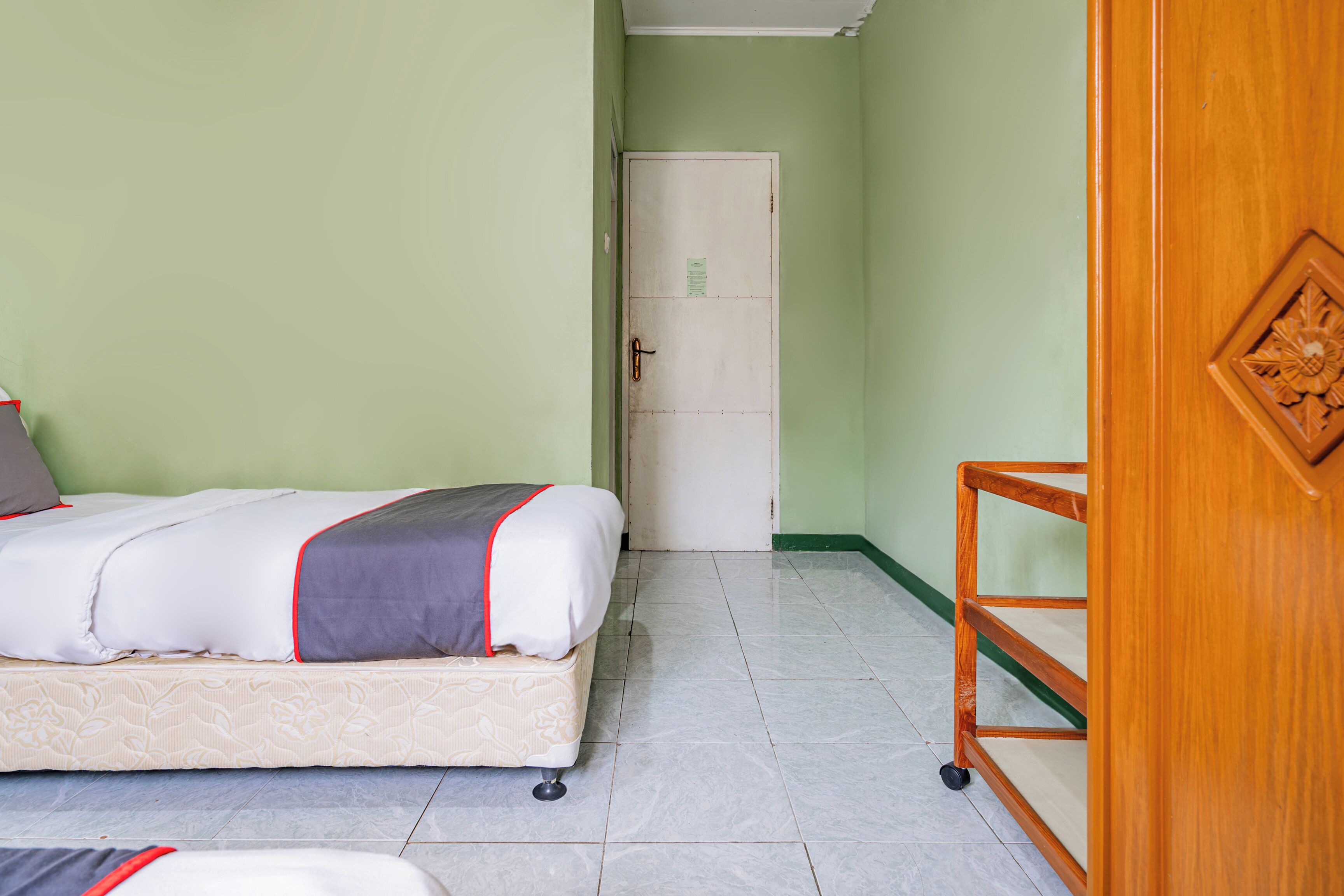 Quarto com uma cama, porta de madeira e uma mesa pequena.