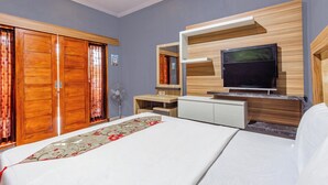 Quarto de hotel moderno com uma cama grande, guarda-roupa de madeira, televisão de tela plana e uma pequena escrivaninha.