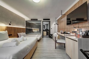 Quarto de hotel moderno com uma cama grande, uma escrivaninha, um espelho e uma televisão.