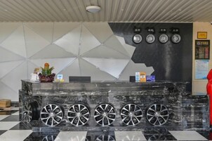 Uma mesa de recepção com design geométrico na parede, um relógio e um mural de avisos.