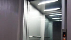 Um elevador moderno com porta de vidro e painel digital exibindo o número do andar.