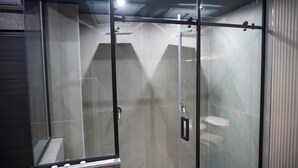 Um chuveiro envidraçado com design moderno, vaso sanitário à mostra e um porta-toalhas.
