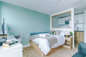 Um quarto moderno com cama, mesa de cabeceira e escrivaninha com cadeira e livros.