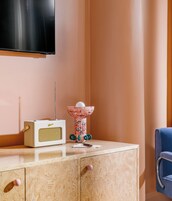 Quarto com um armário de madeira, um rádio antigo e um objeto decorativo em cima.