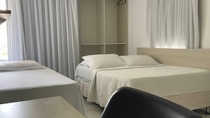 Quarto de hotel com cama, escrivaninha e guarda-roupa.
