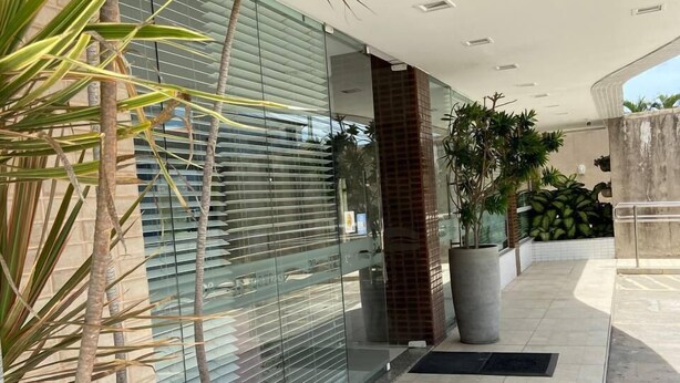 Um edifício moderno com grandes janelas de vidro, plantas em vasos e piso revestido de azulejos.