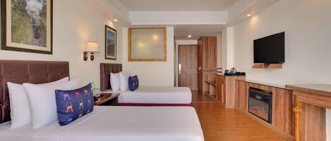 Quarto de hotel com duas camas, televisão, lareira e cozinha.