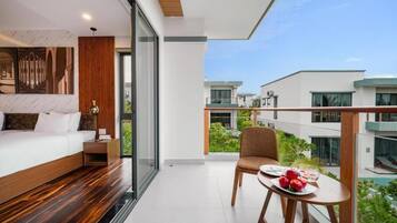 Varanda moderna com sofá branco, mesa de madeira com frutas e vista para edifícios próximos.