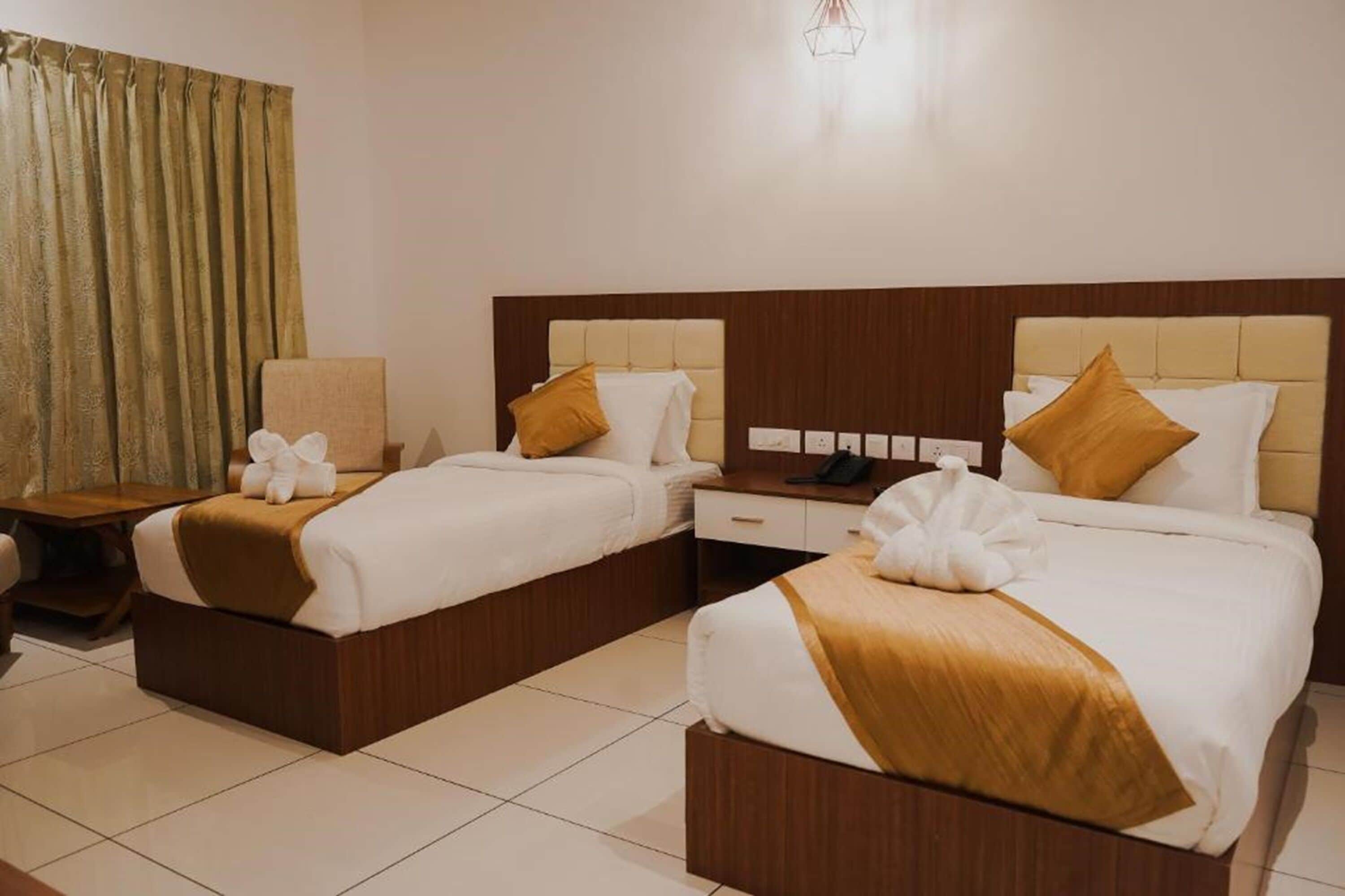 Quarto de hotel com duas camas, uma mesa de cabeceira, uma escrivaninha e uma cadeira.
