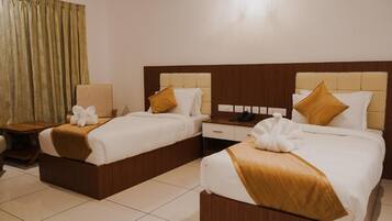 Quarto de hotel com duas camas, uma mesa de cabeceira, uma escrivaninha e uma cadeira.