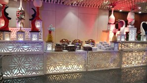 Uma área de recepção com vasos decorativos, teto estampado e um balcão com diversos objetos.