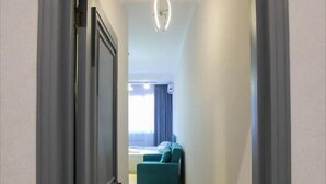Corredor que leva a um quarto com um sofá azul e uma luminária moderna.