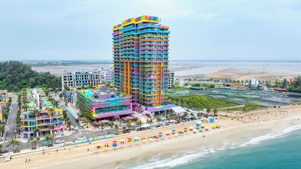 Um hotel alto e colorido com várias varandas, localização à beira-mar e vista para o oceano.