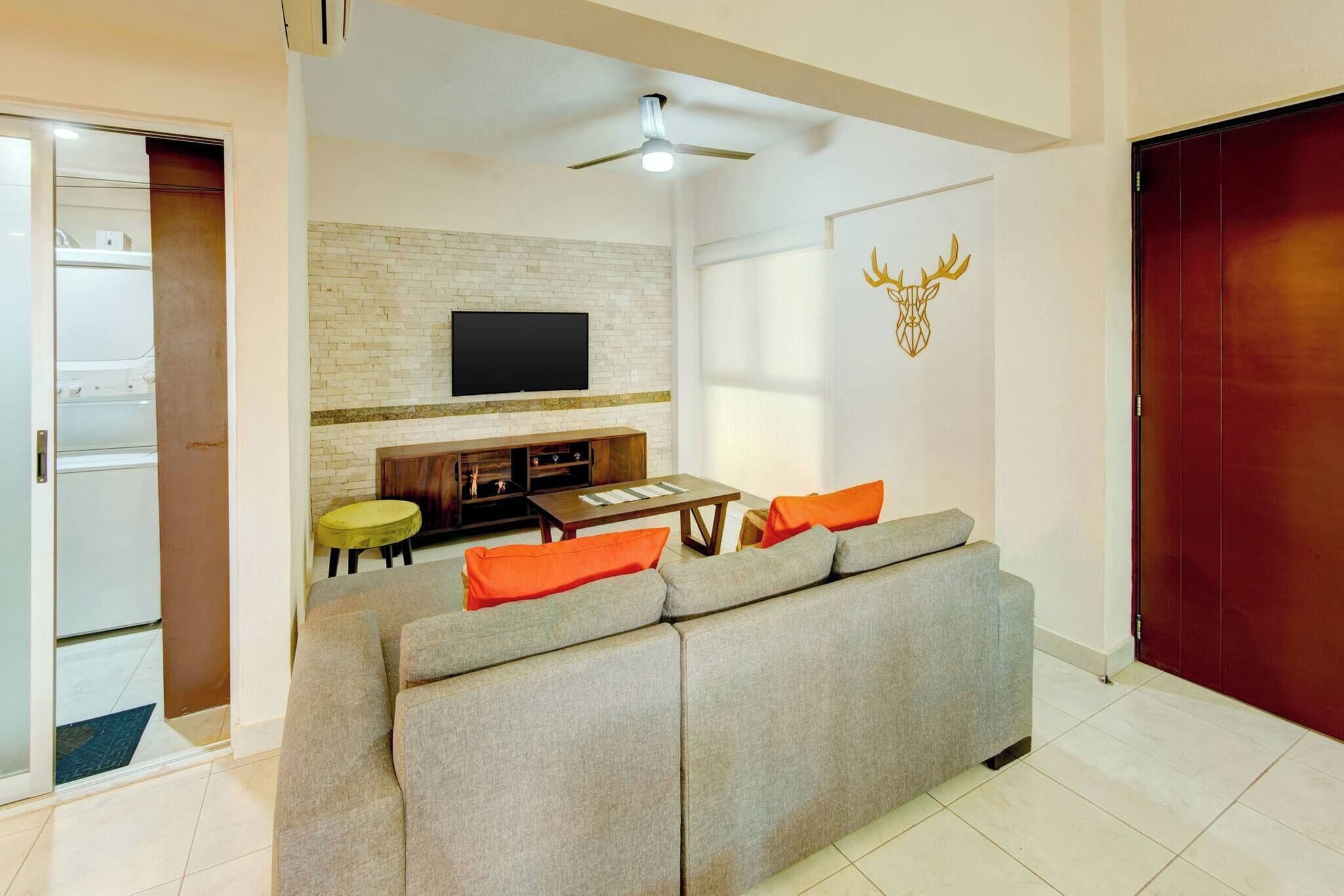Uma sala de estar com sofá, mesa, televisão de tela plana e lareira.