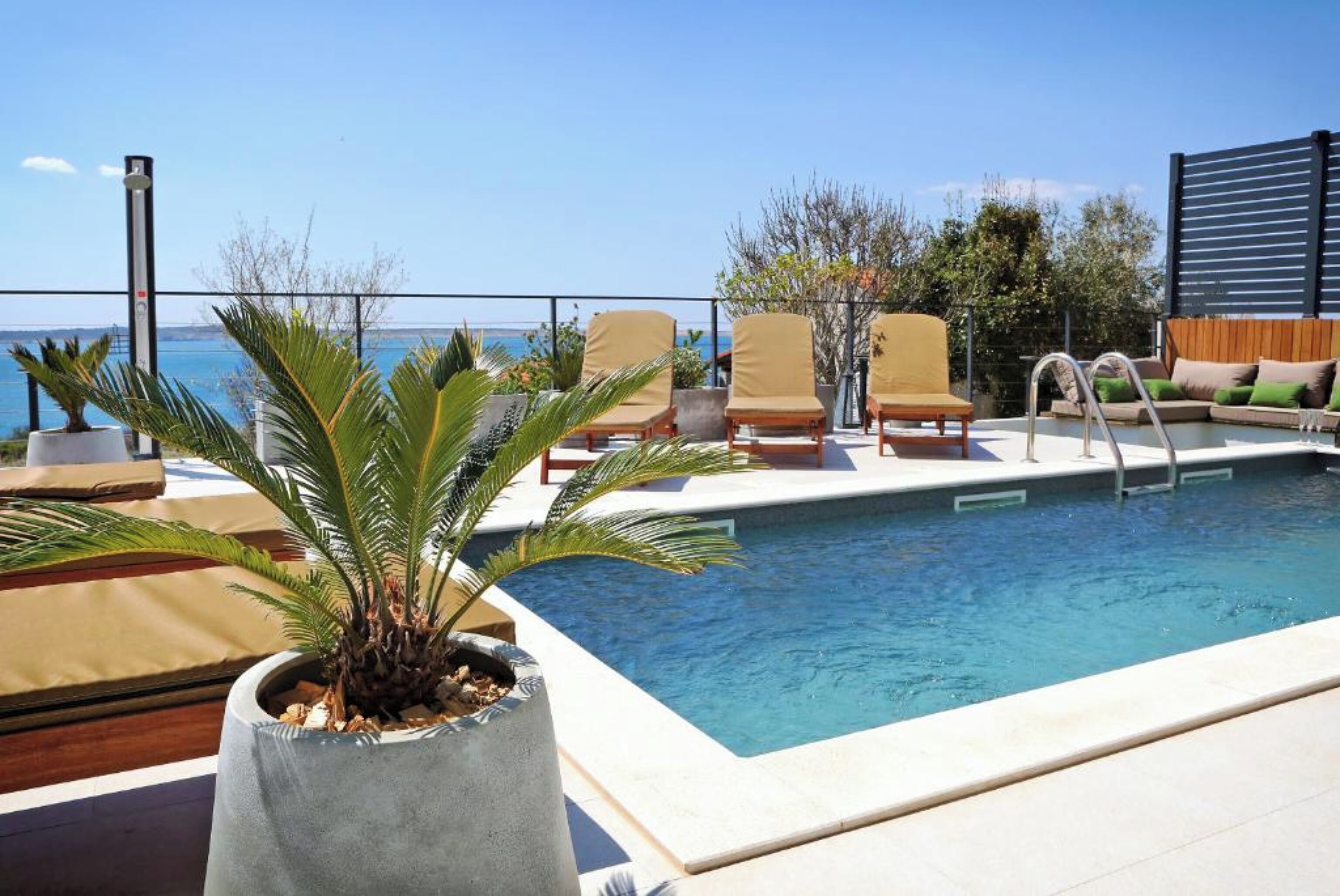 Uma área de piscina com espreguiçadeiras e um vaso de planta.