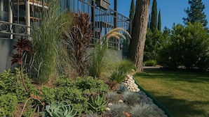 Um jardim com paisagismo, com diversas plantas e um caminho de pedra que leva a um edifício.